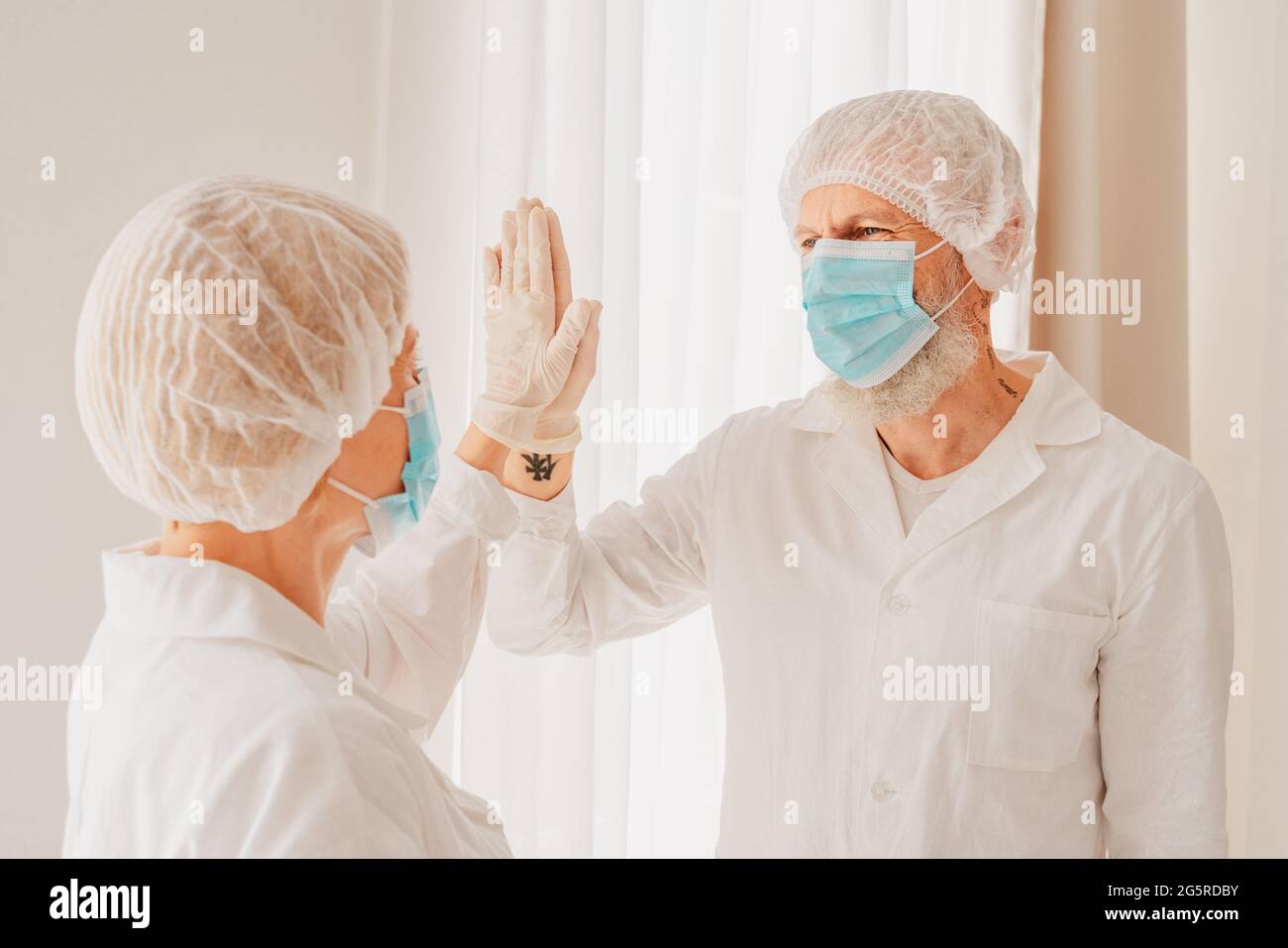 Doctors with mask and face protector give each other a 5 with their ...