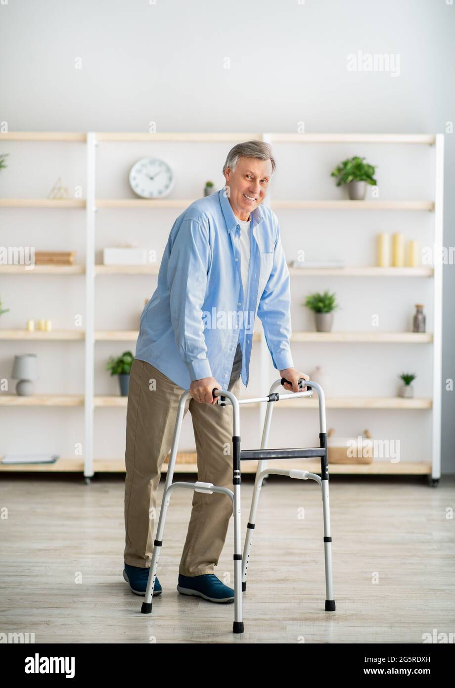 Full length portrait of elderly man walking with frame at retirement ...