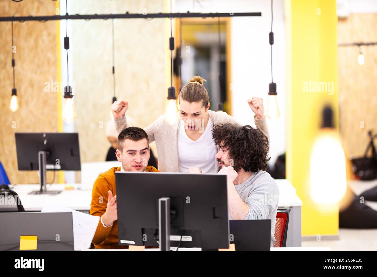 Three caucasian colleagues cheering for job well done in a modern ...