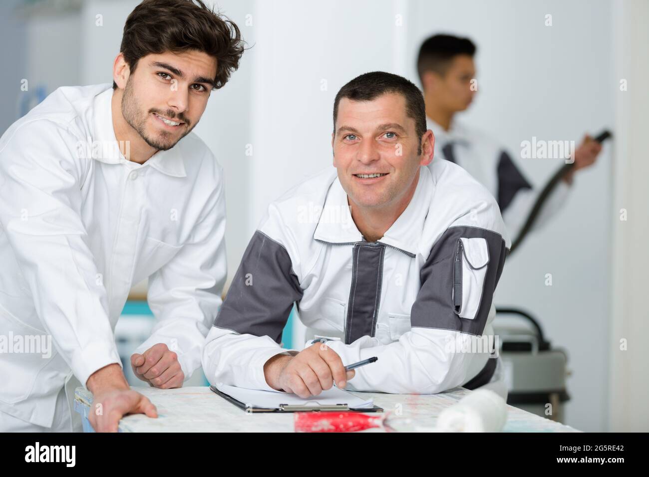 renovation apprentice posing and smiling with teacher Stock Photo - Alamy