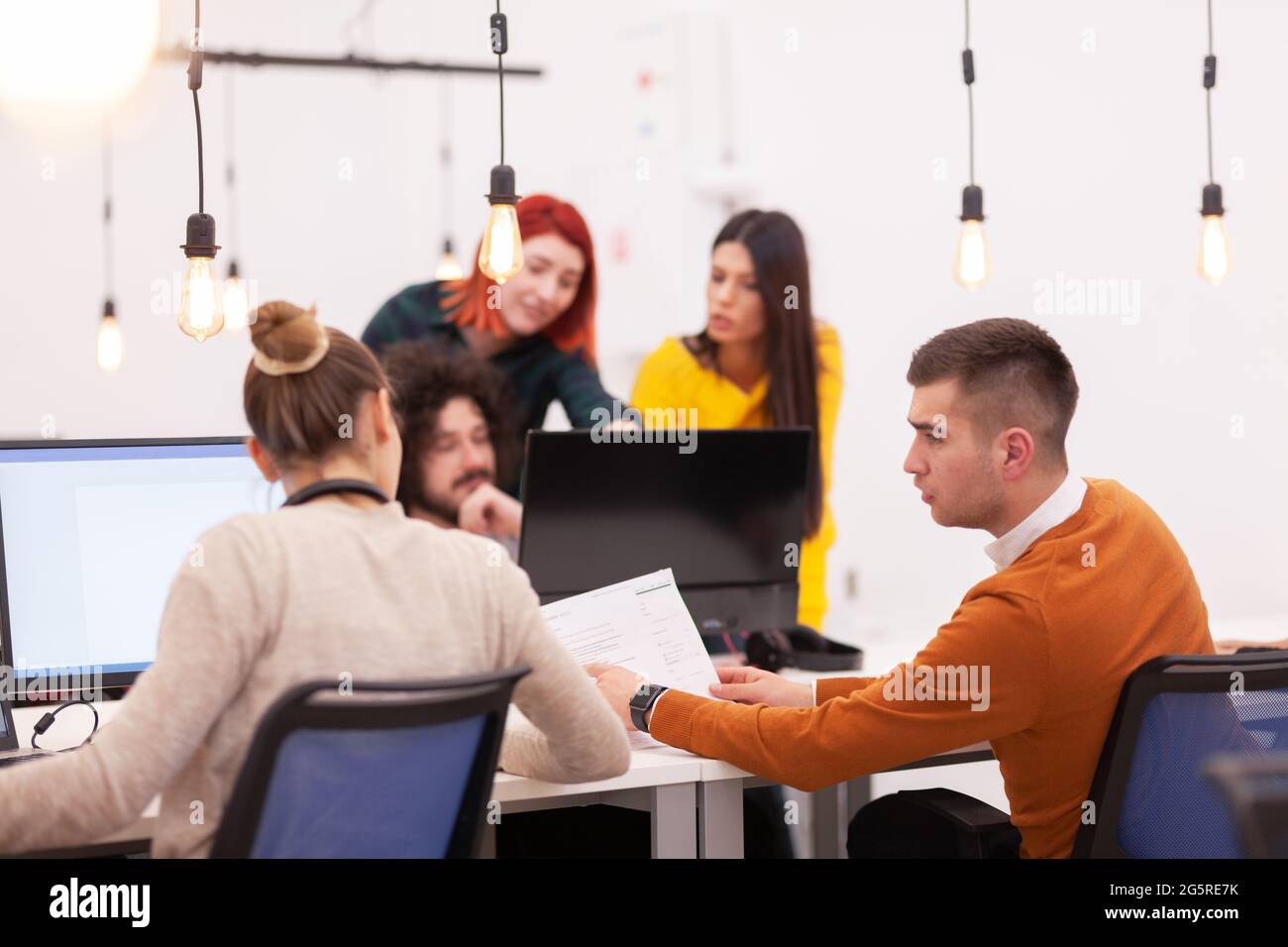 Group of multiethnic colleagues working on desktop computers in a ...