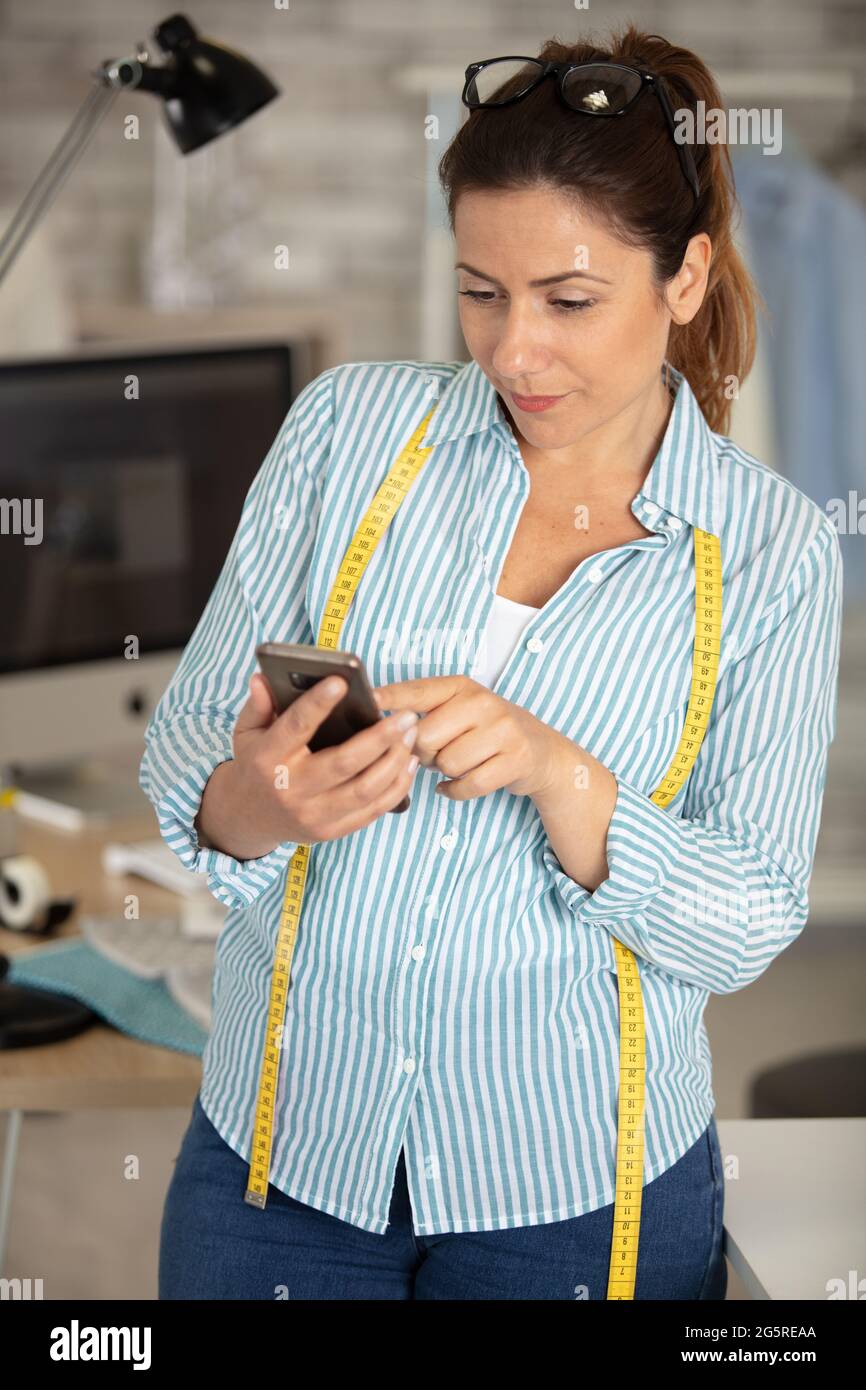 stylist is working in sewing factory using mobile phone Stock Photo - Alamy
