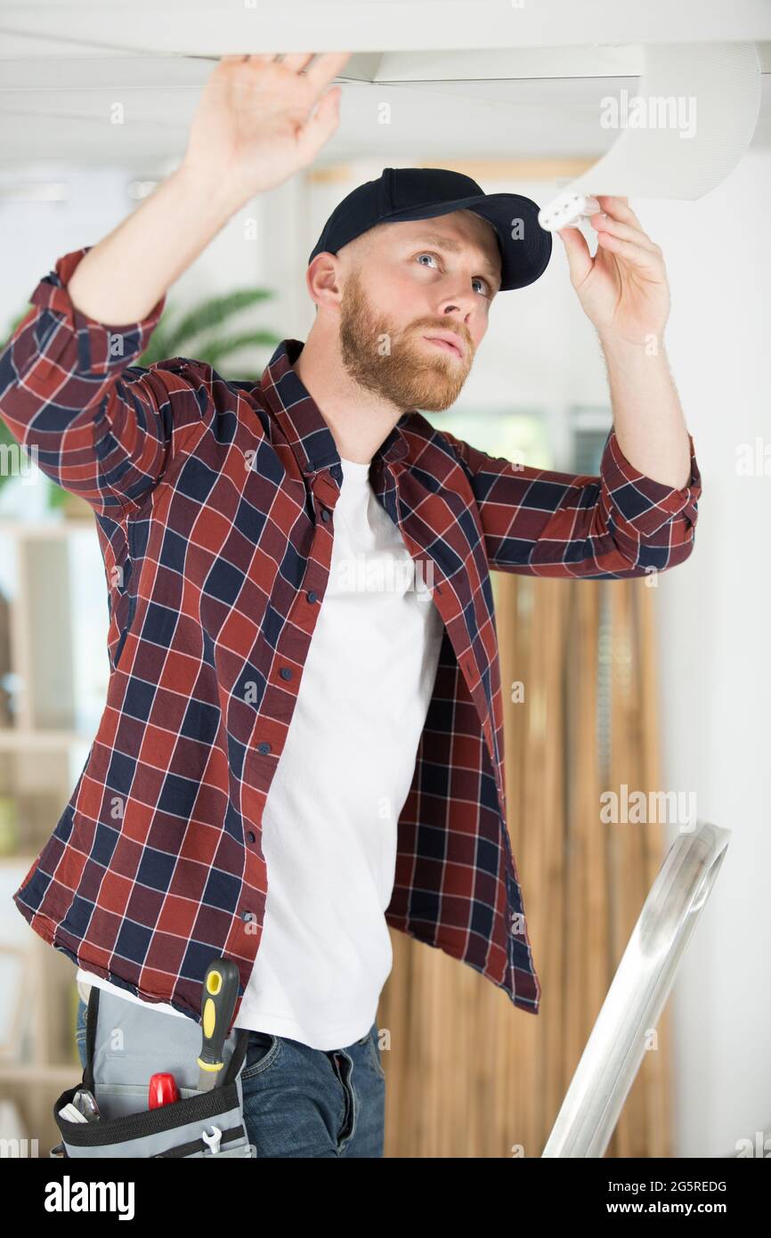young handyman installing a new bulb in ceiling light Stock Photo - Alamy