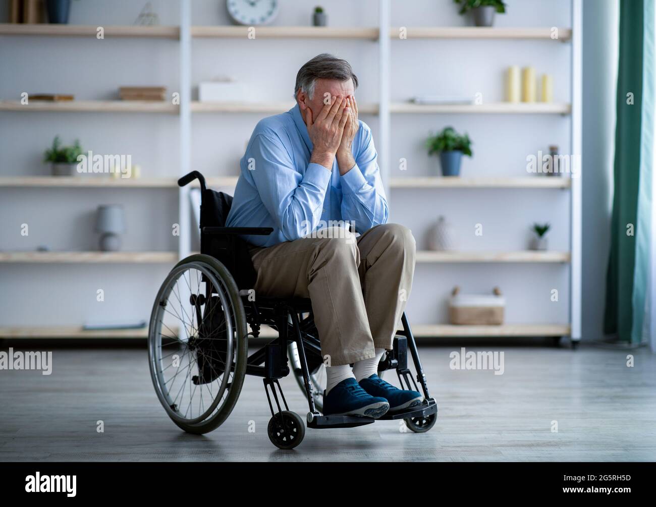 Sad and lonely older impaired man in wheelchair crying at retirement ...