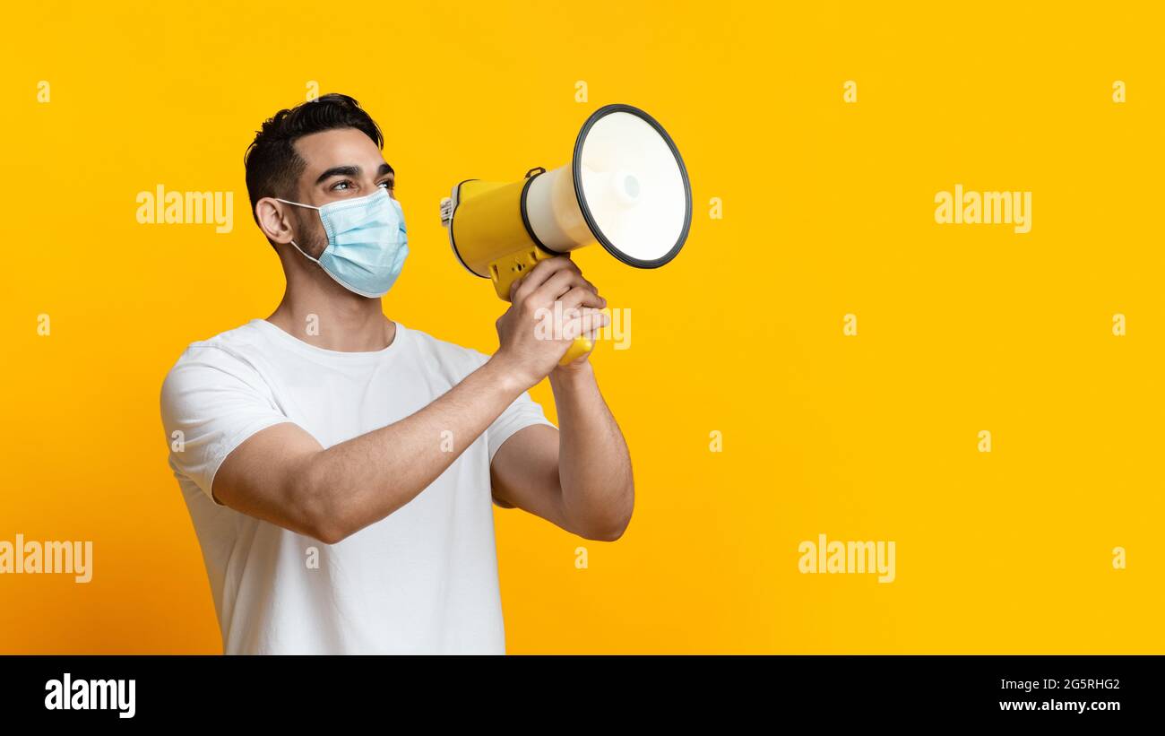 Arab guy with protective face mask using megaphone Stock Photo - Alamy
