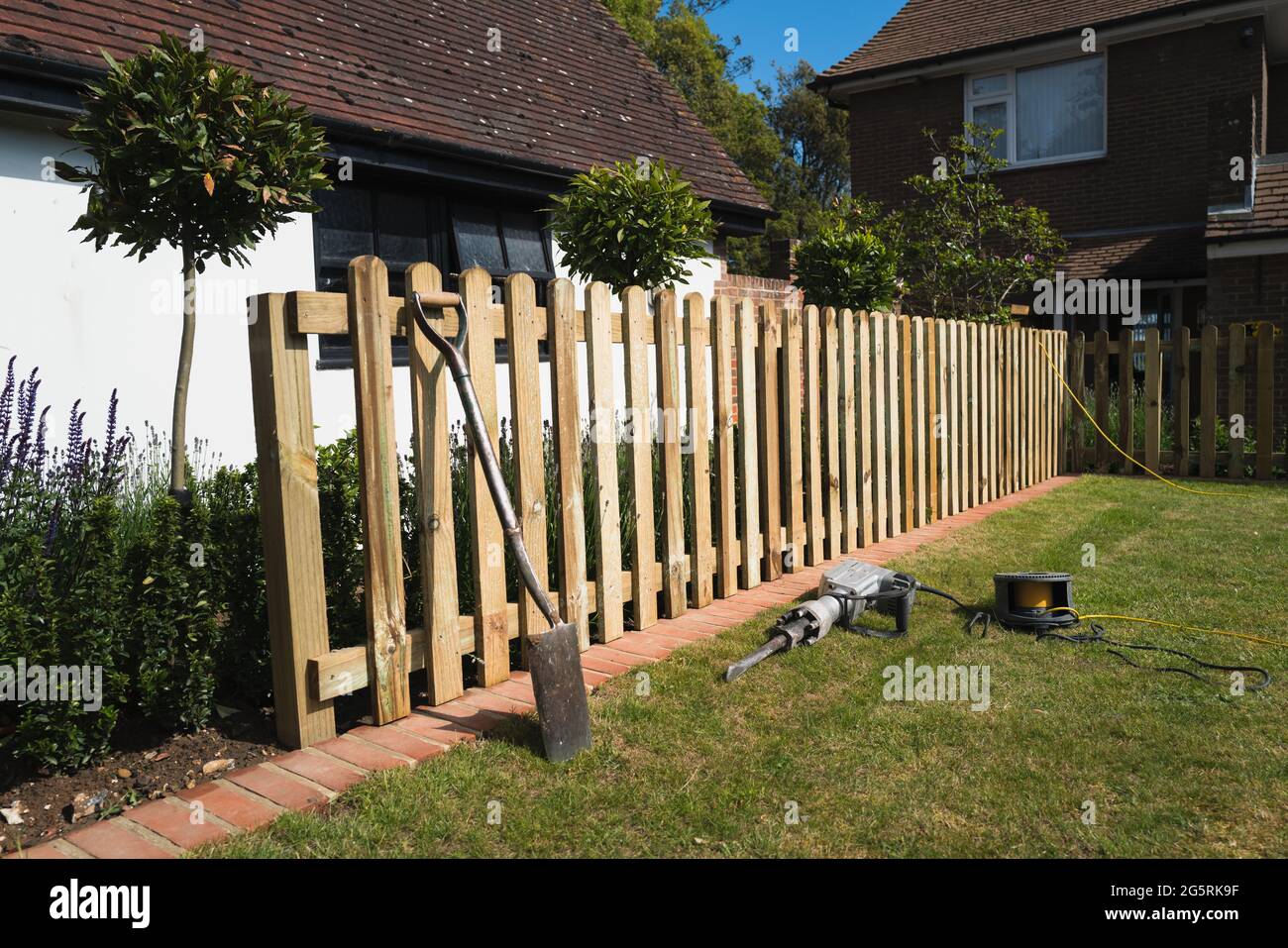 The installation of a wooden, natural wood colour, picket fence in a ...