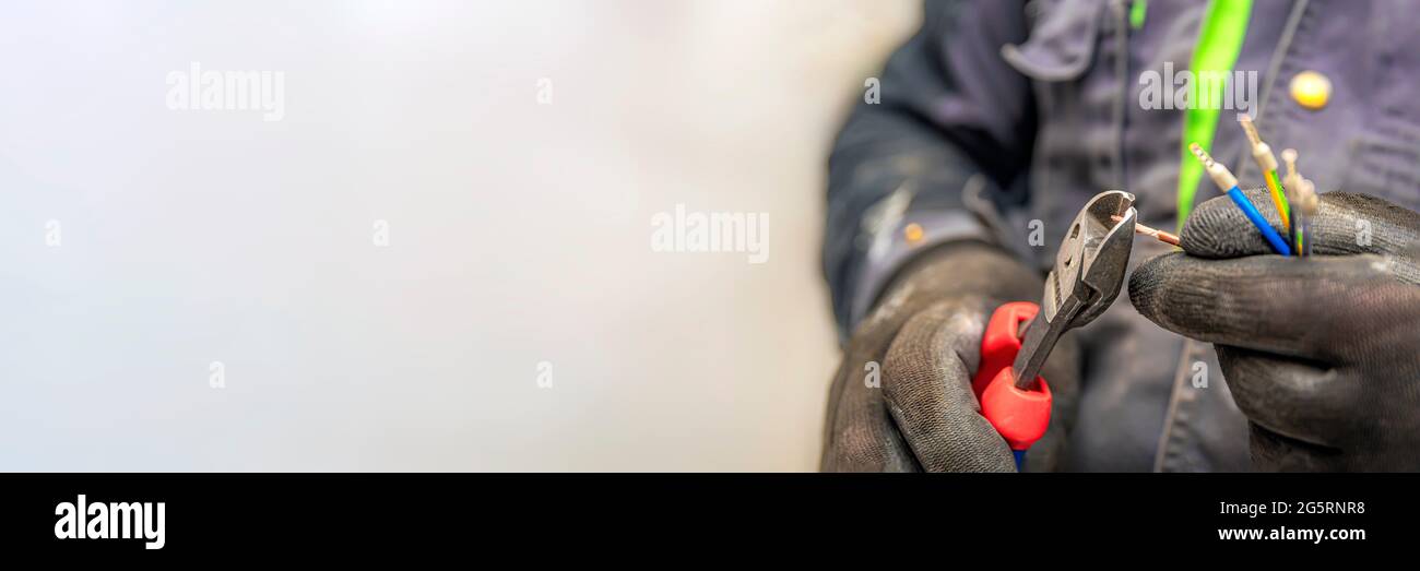 Electrician hands hold wire cutters and close-up of wires. The idea of ...
