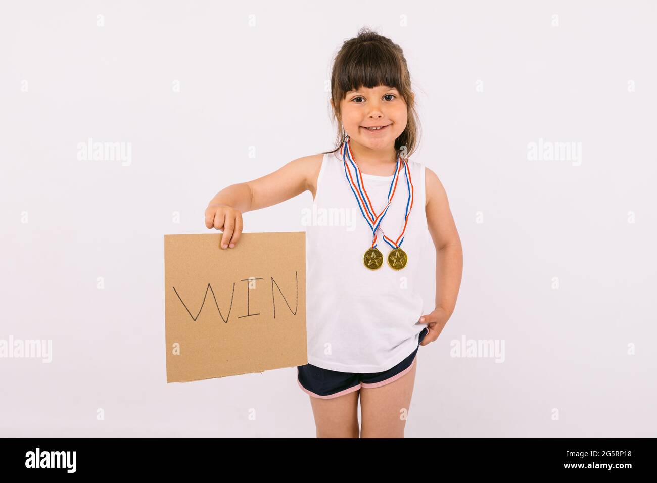 Small dark-haired girl with sports champion medals, holding a sign that ...