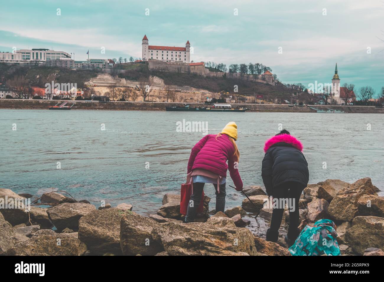 two children playing by the river Danube with views to the Bratislava ...