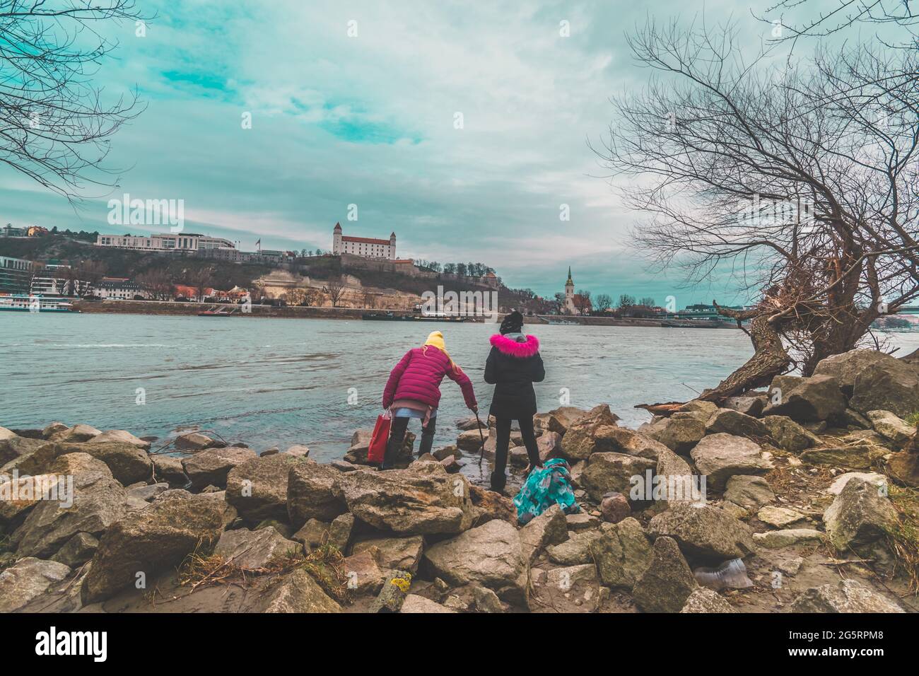 two children playing by the river Danube with views to the Bratislava ...