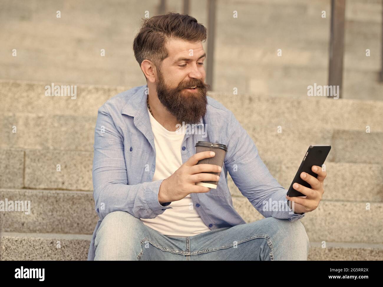 Handsome bearded man relaxing mobile phone and coffee cup. Modern ...