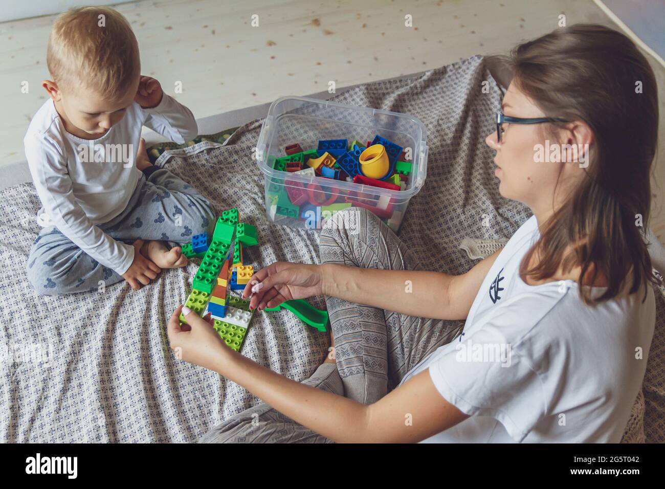 Mom and kid play together in the bedroom with plastic blocks Stock ...