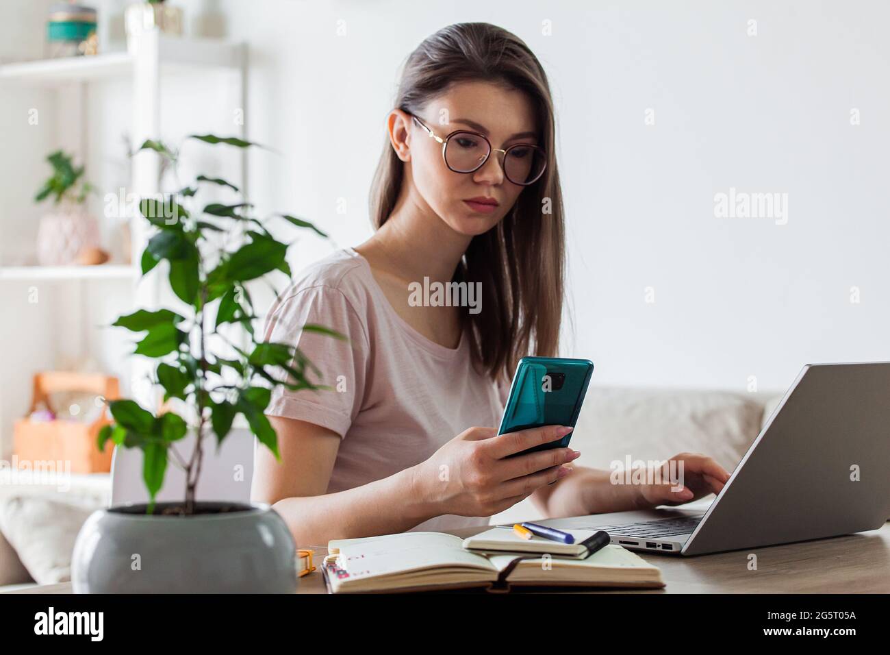Young woman using mobile phone and laptop to work home, multiple ...