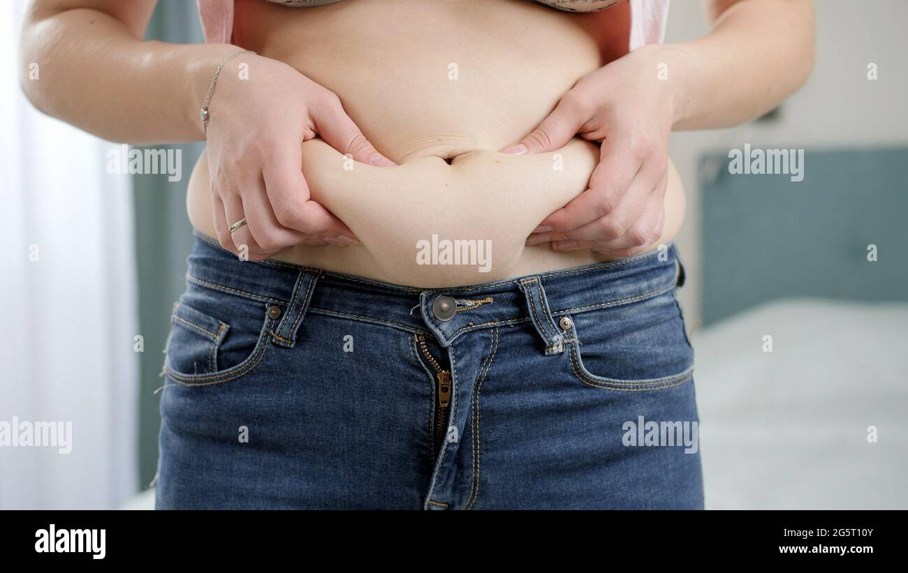 Young woman with big belly looking at her overweight body. Concept of ...