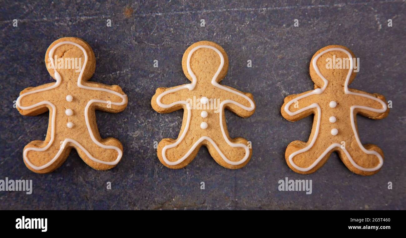 A Line of Three Decorated Gingerbread Men on a Dark Surface Stock Photo ...