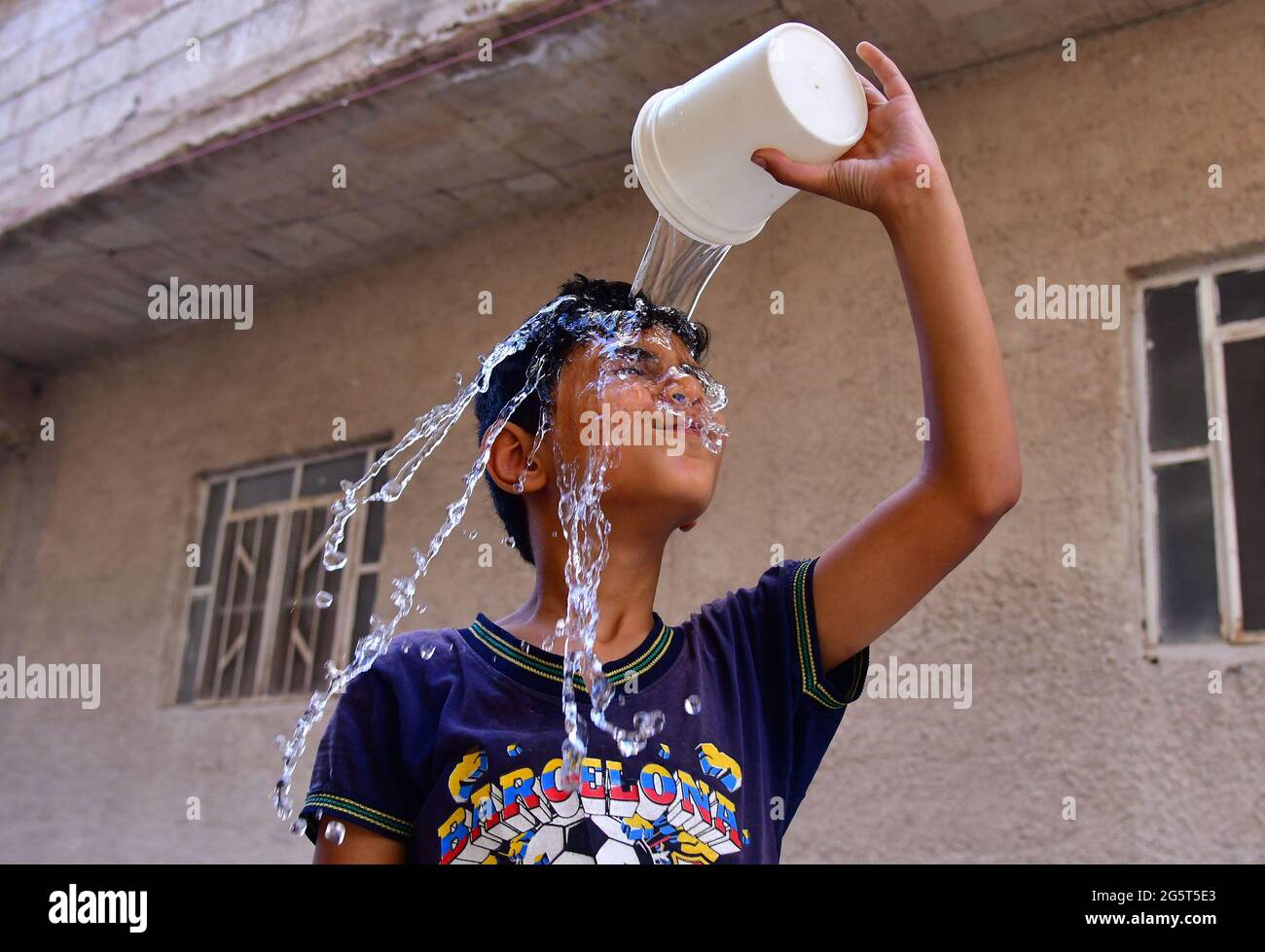 Damascus, Syria. 29th June, 2021. A Syrian boy cools off with water ...