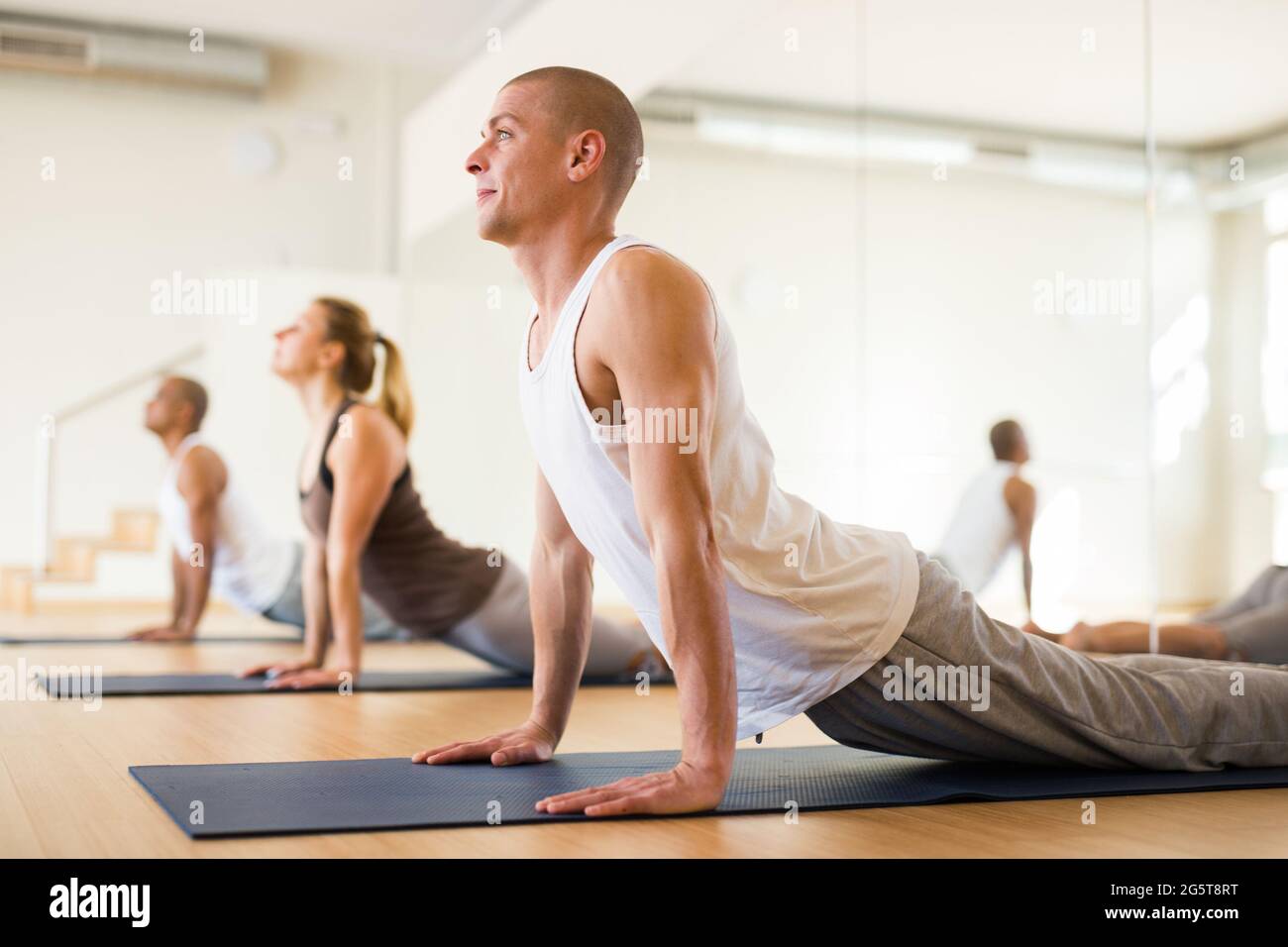 Nice people exercising during yoga class in fitness center Stock Photo ...