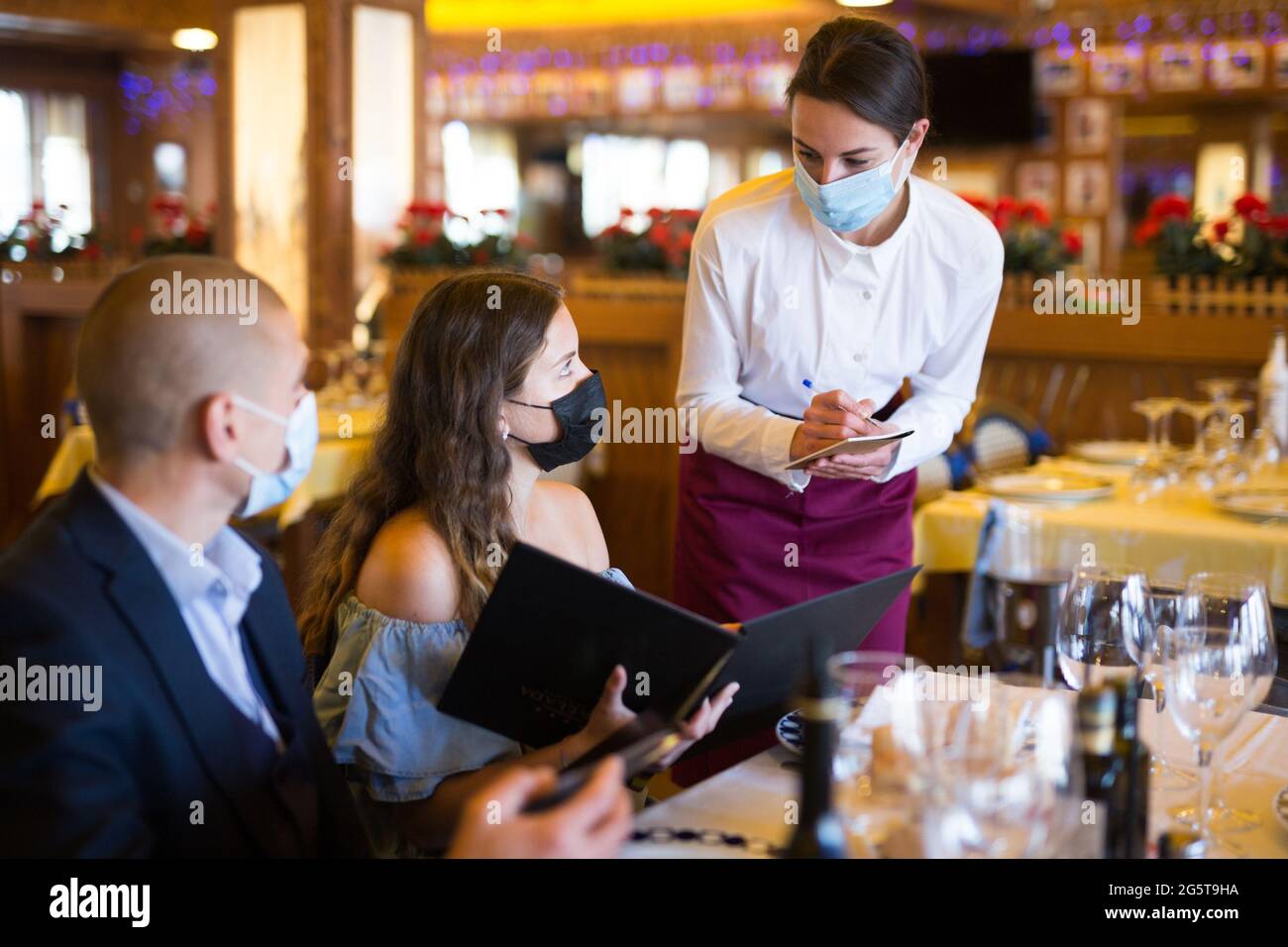 Positive young couple making order at restaurant Stock Photo - Alamy