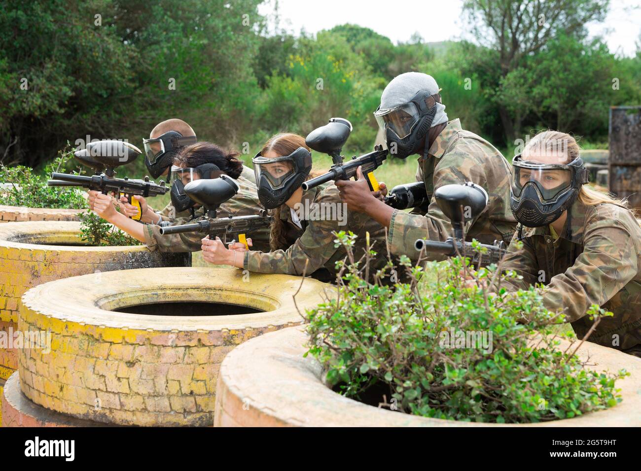 Group of friends paintball players of opposite teams in shootout in ...