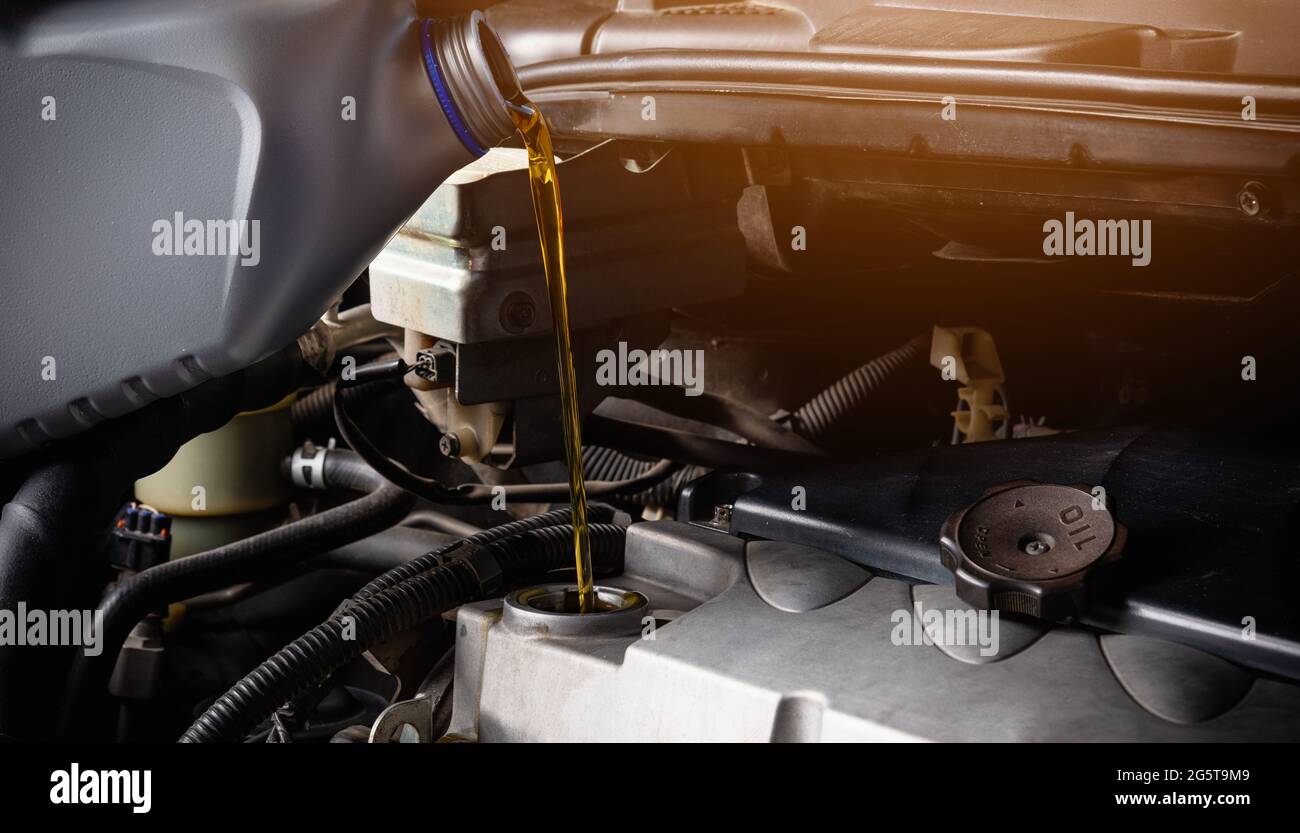 Hand mechanic in service to repair a car, pouring change lubricant oil ...