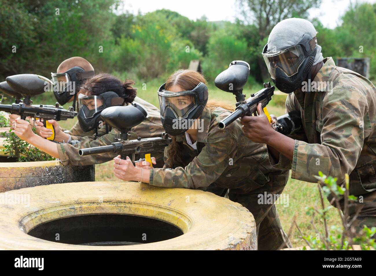 Group of paintball players aiming and shooting with guns Stock Photo ...