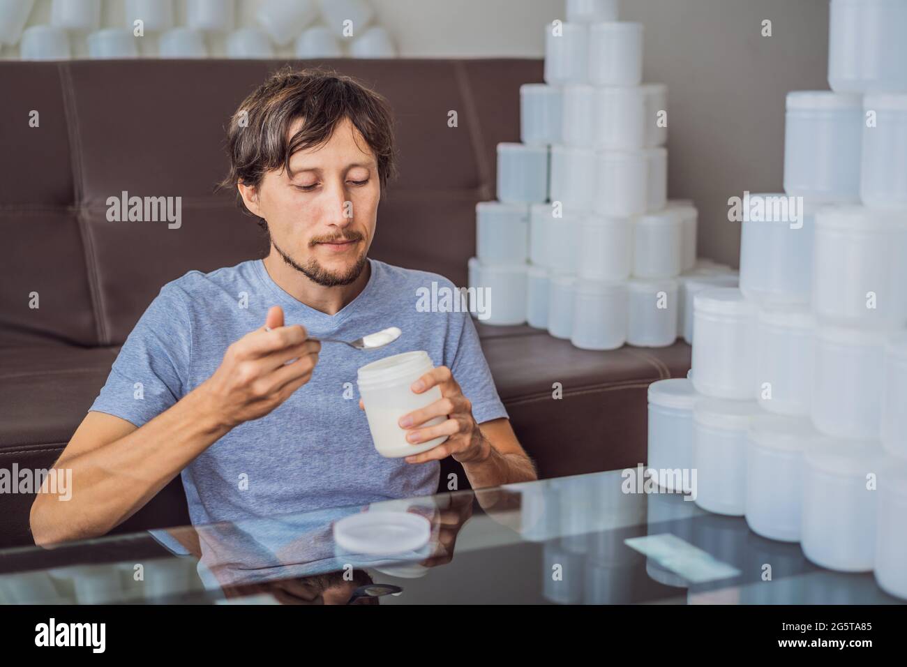 The man eats yogurt and is surrounded by many jars of yoghurt that he ...