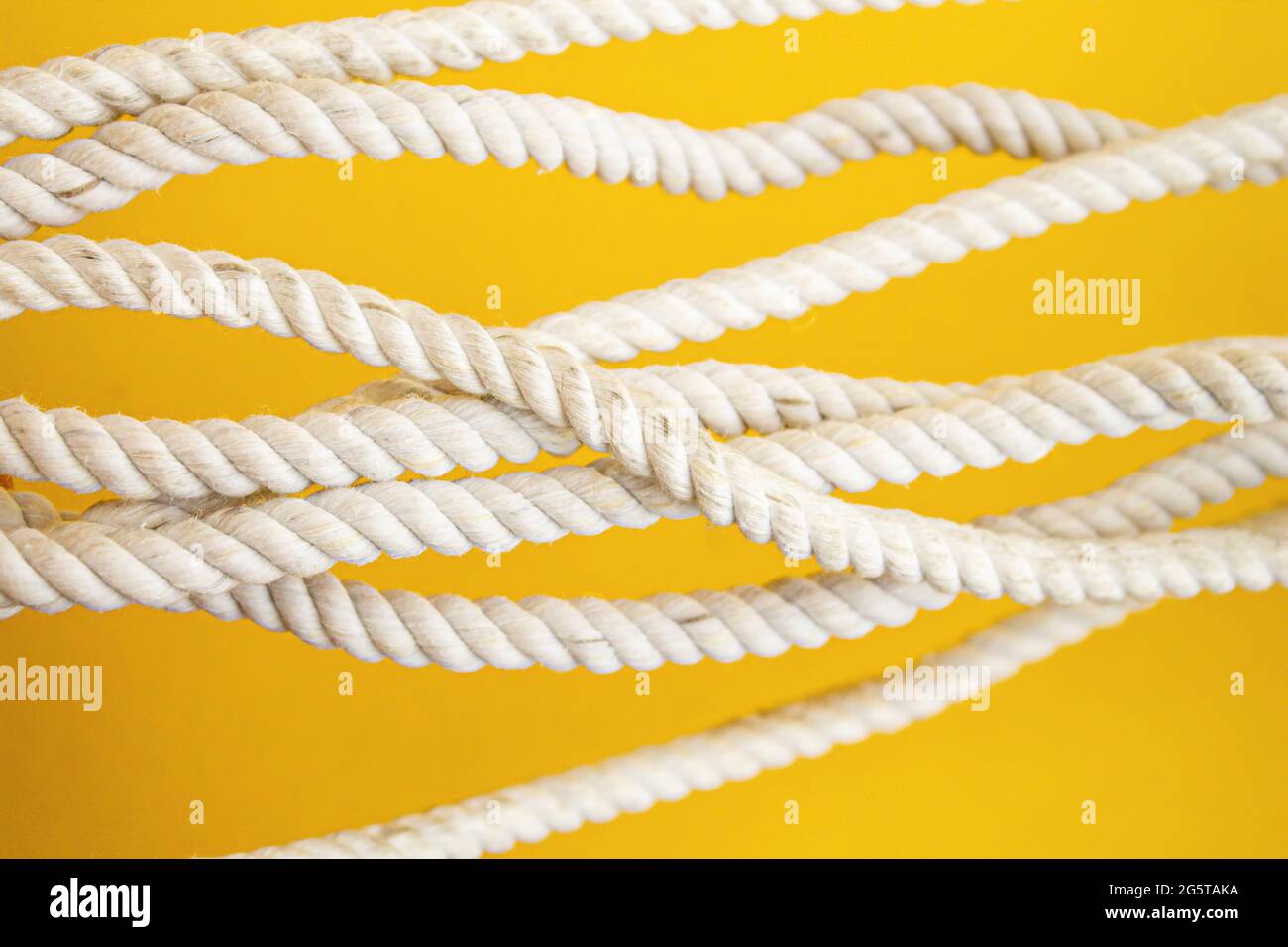 White rope on a yellow background. Rope close-up. The rope sections are ...