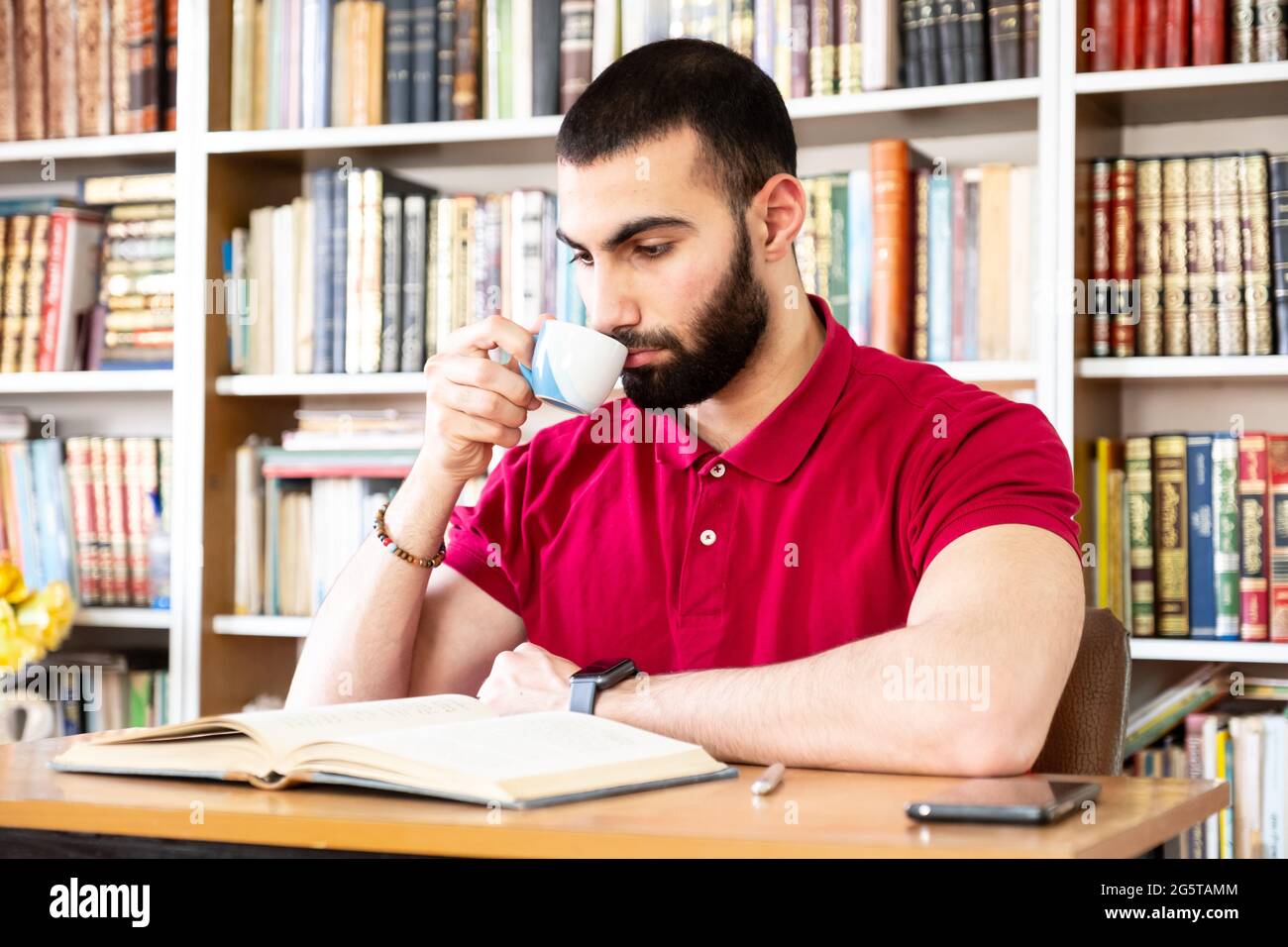 Man reading a book and drinking in the library Stock Photo - Alamy