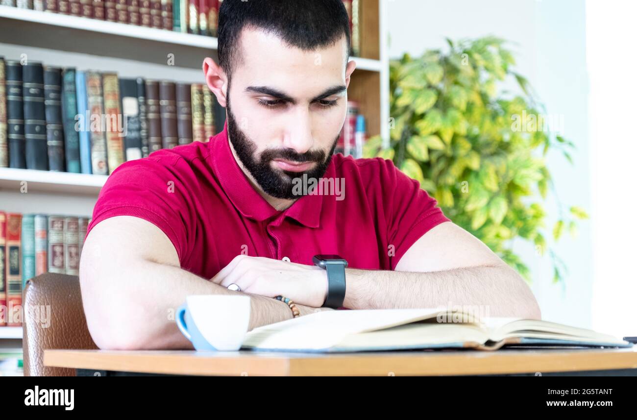 Man reading a book and drinking in the library Stock Photo - Alamy