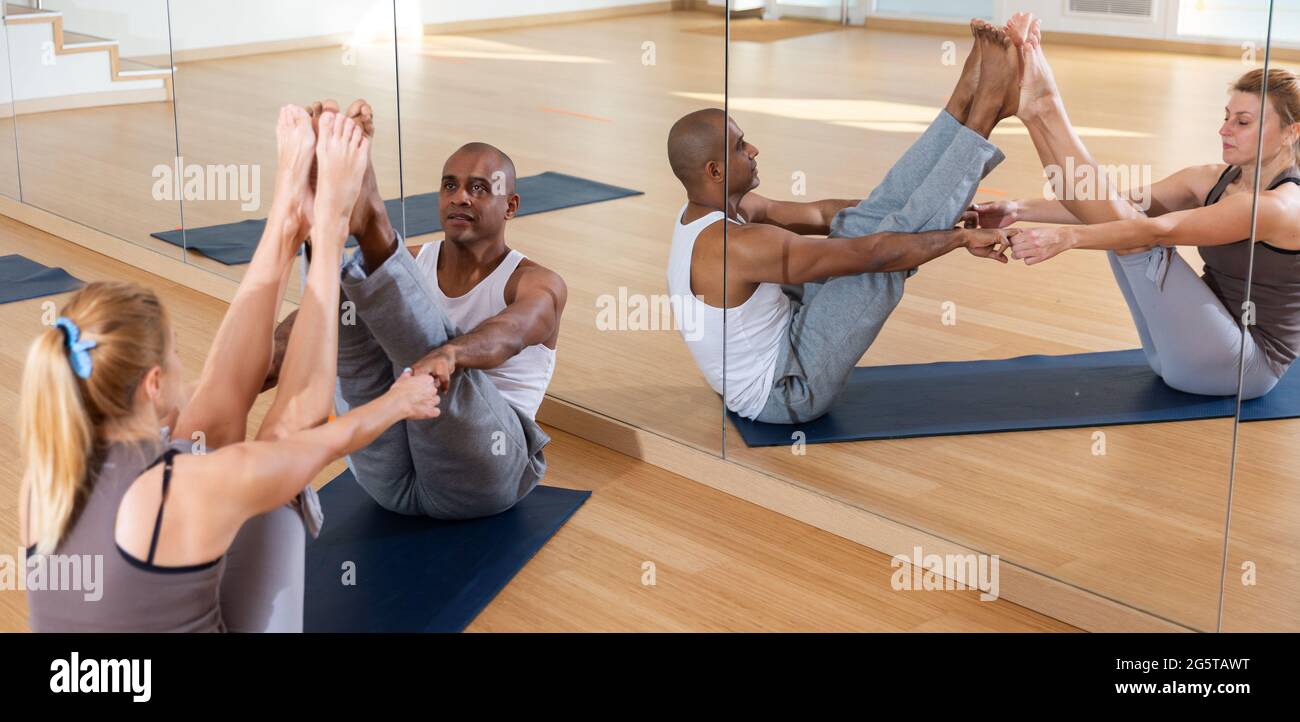 Yoga teacher helps couples learn yoga poses Stock Photo - Alamy