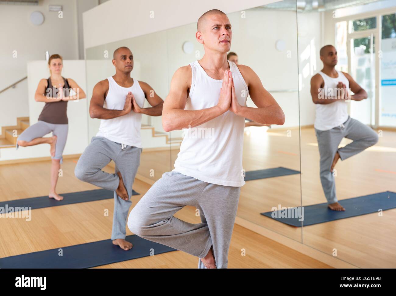 Man standing in Eka Pada Pranamasana during group yoga training Stock ...