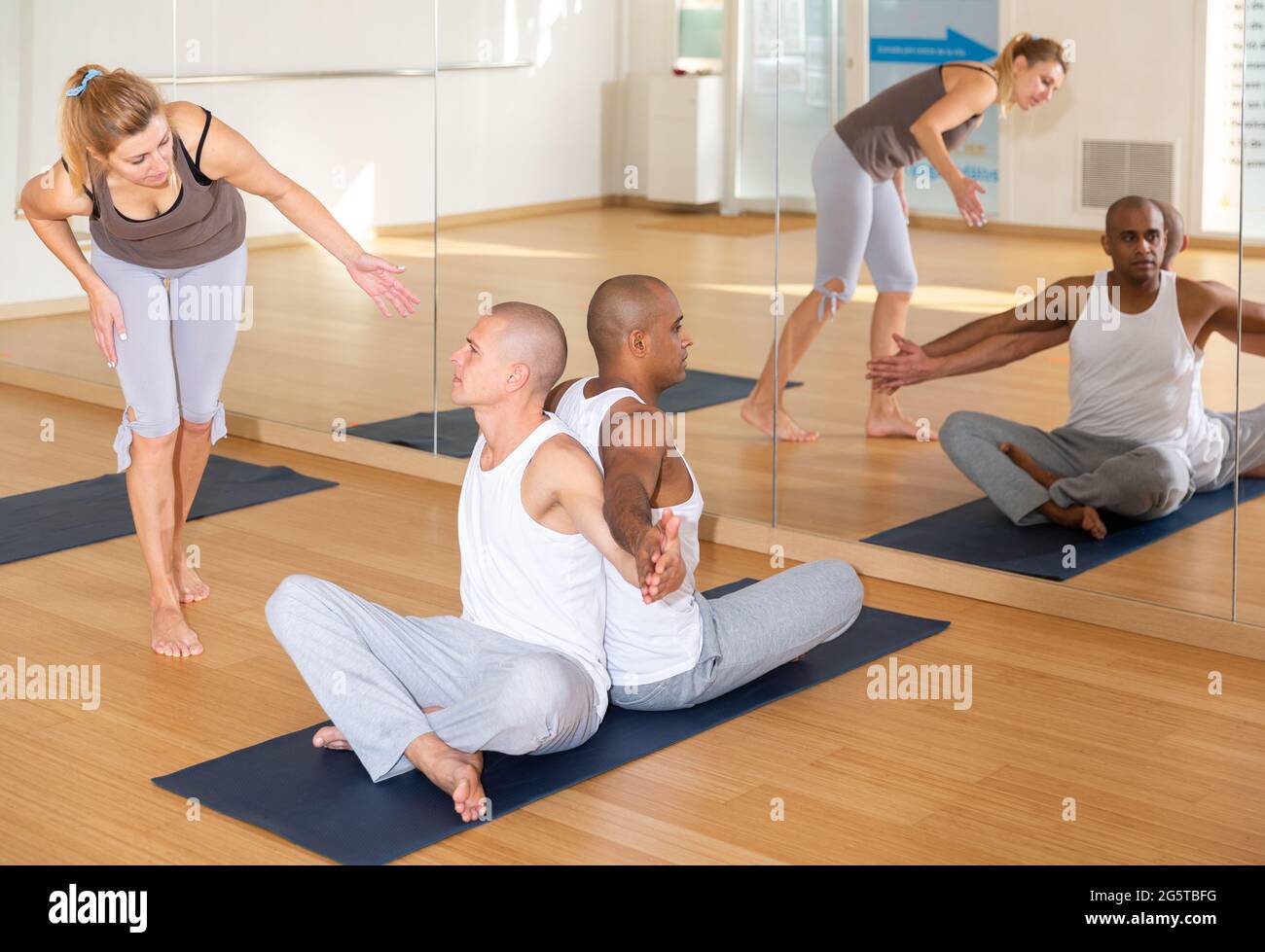 Yoga teacher helps couples learn yoga poses Stock Photo - Alamy