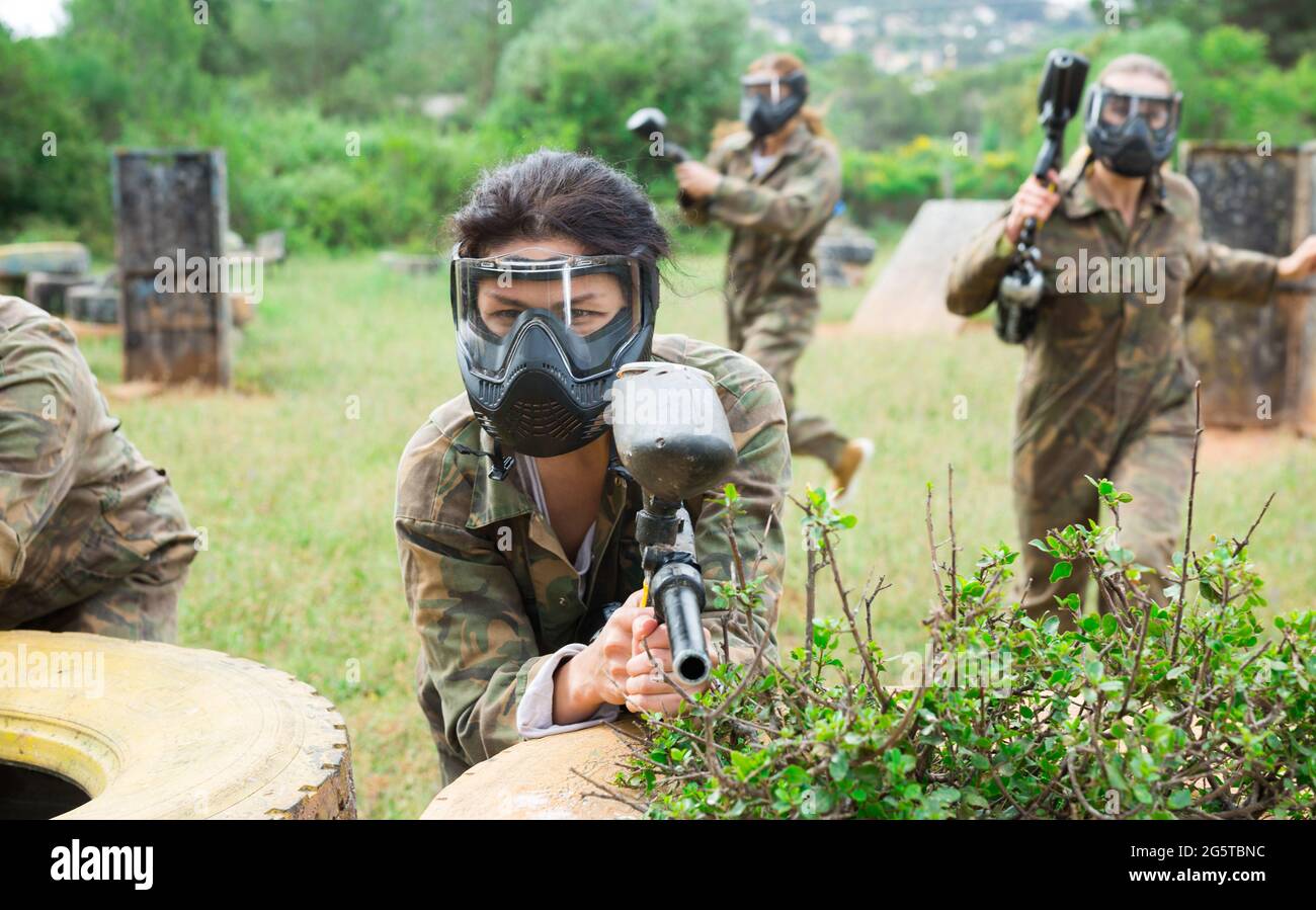 Excited male and female paintball players in protective uniform aiming ...