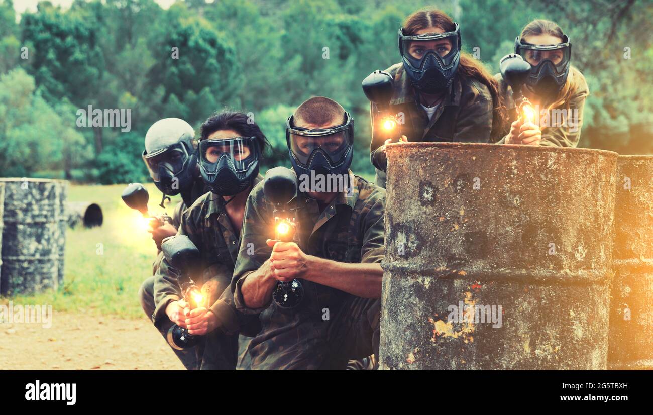 Group of paintball players aiming and shooting with guns Stock Photo ...