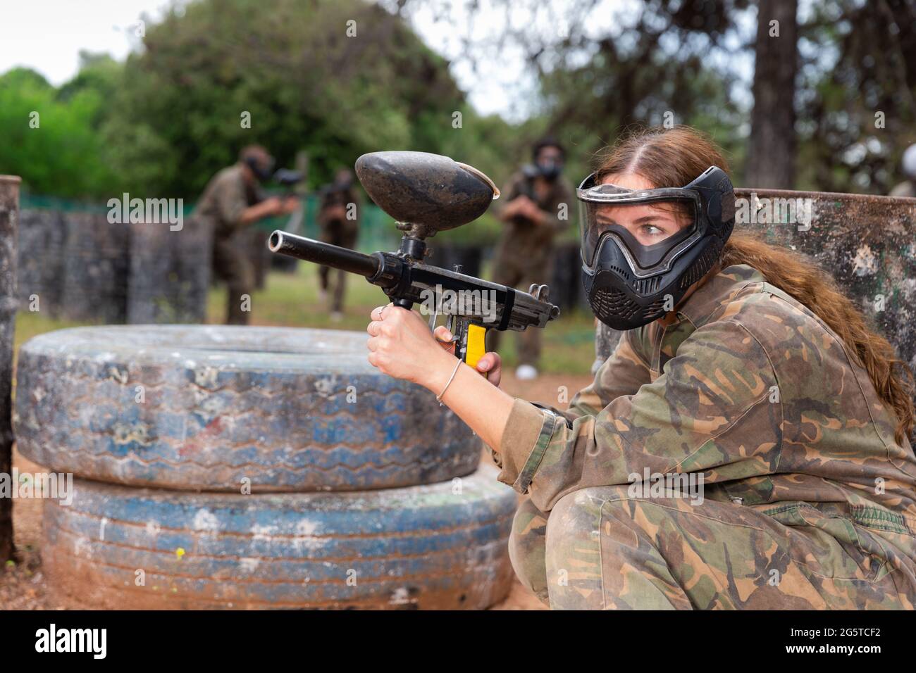 Paintball players of one team in camouflages and masks aiming with gun ...