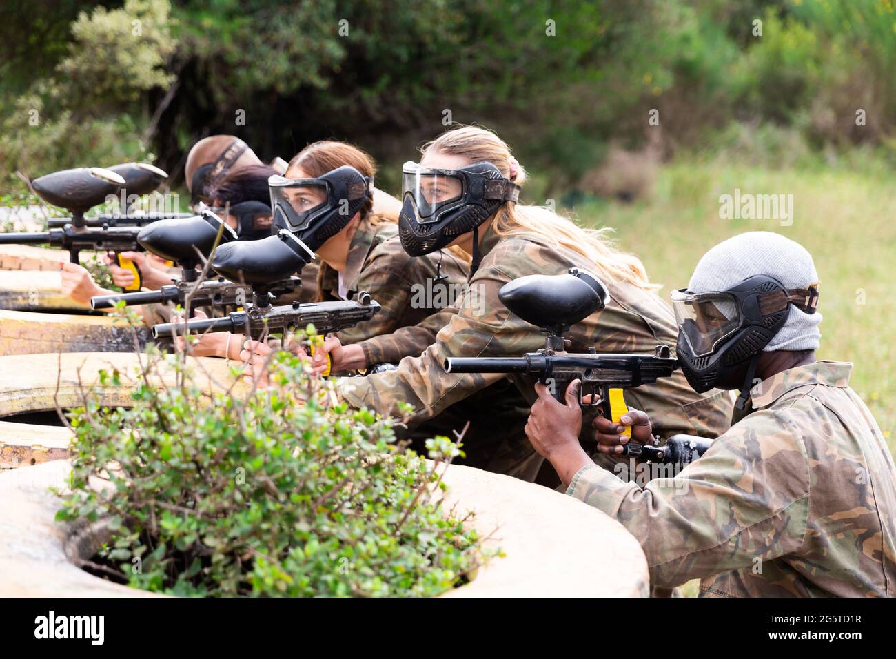 Group of paintball players aiming and shooting with guns Stock Photo ...