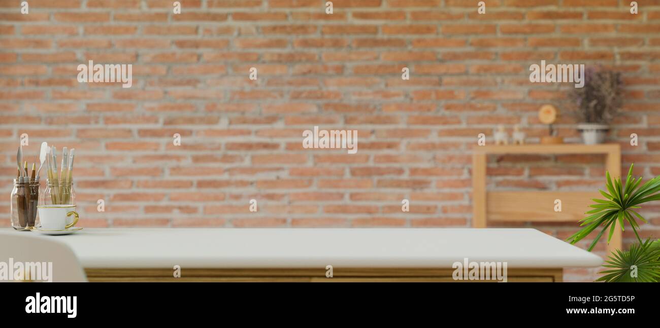 Craft table with copy space and paint tools in home office with brick ...