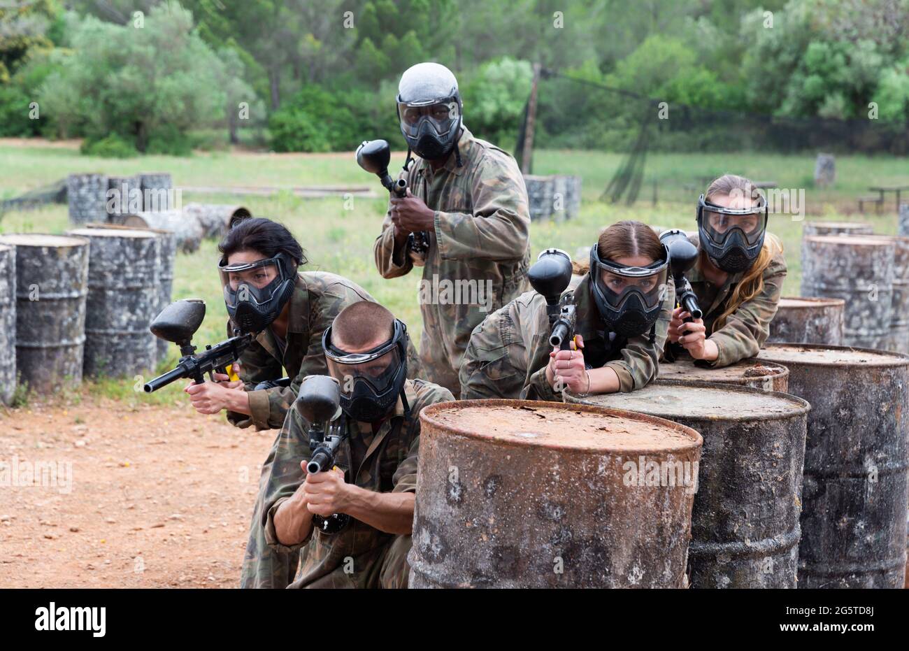 Group of people in full gear playing paintball on shooting range ...
