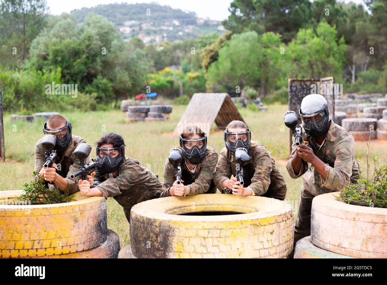 Group of paintball players aiming and shooting with guns Stock Photo ...