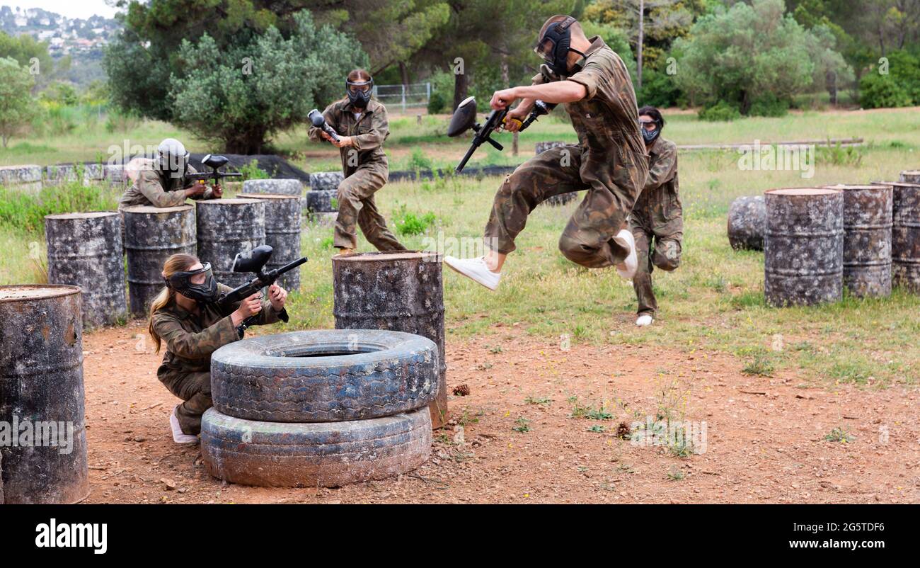 Excited male and female paintball players in protective uniform aiming ...