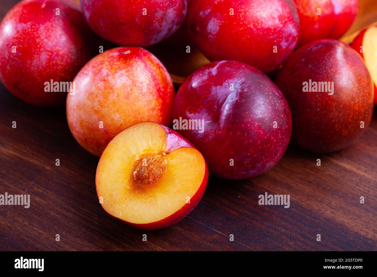 Whole and halves red appetizing plums Stock Photo - Alamy