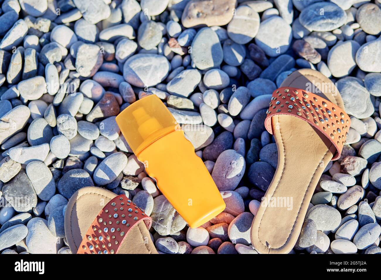 Mock up of sun cream, summer slippers and hat on the beach. Concept of ...