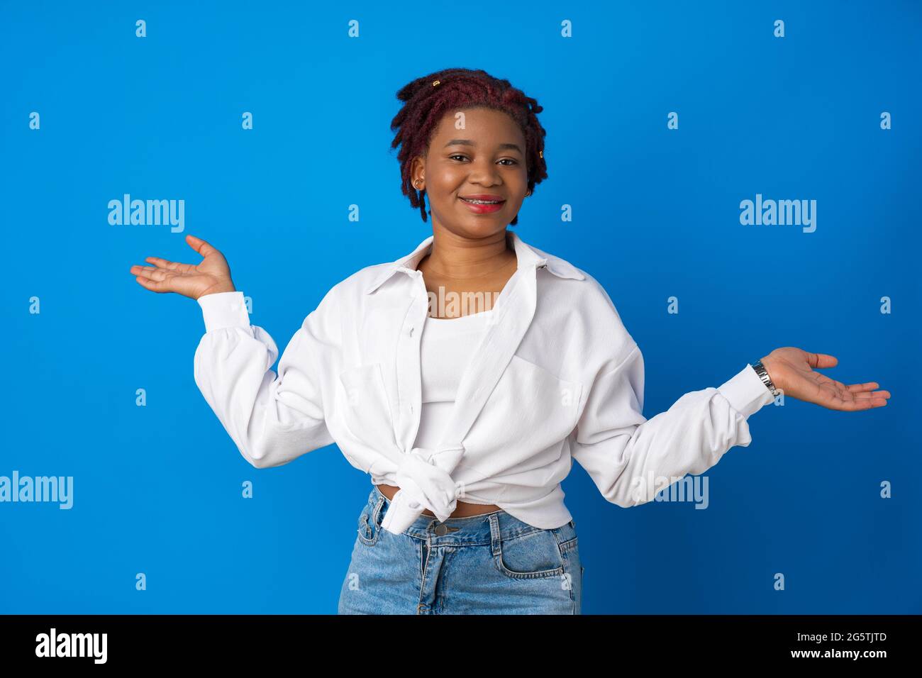 Hesitant african american woman shrugging her shoulders against blue ...