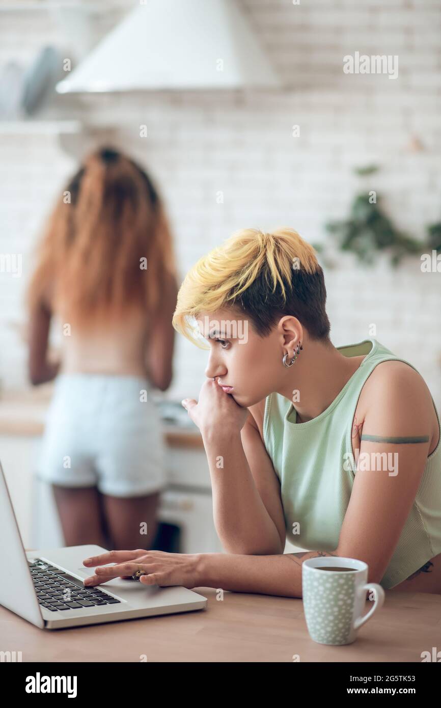 Pensive woman behind laptop and girlfriend at distance Stock Photo - Alamy