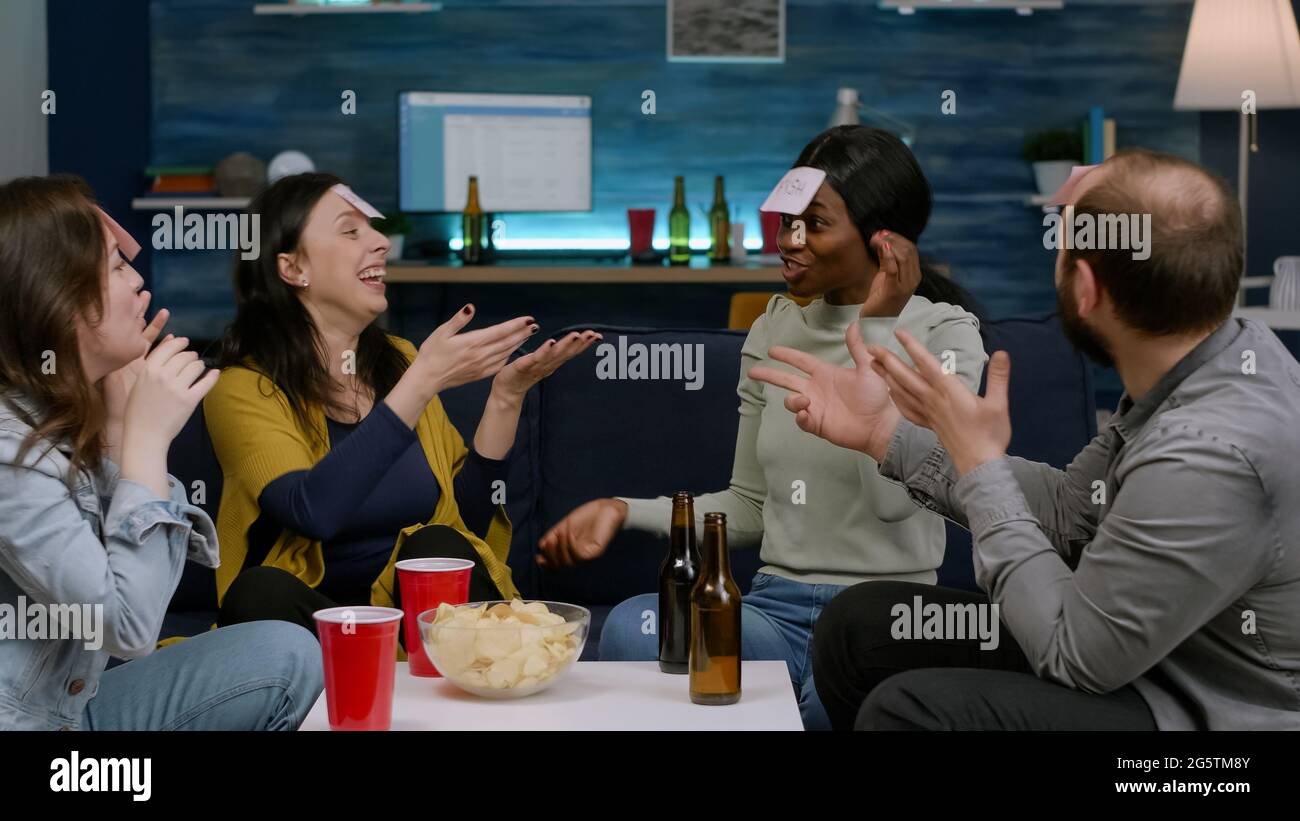 Multiracial group playing Guess who game with sticky papers attaching ...