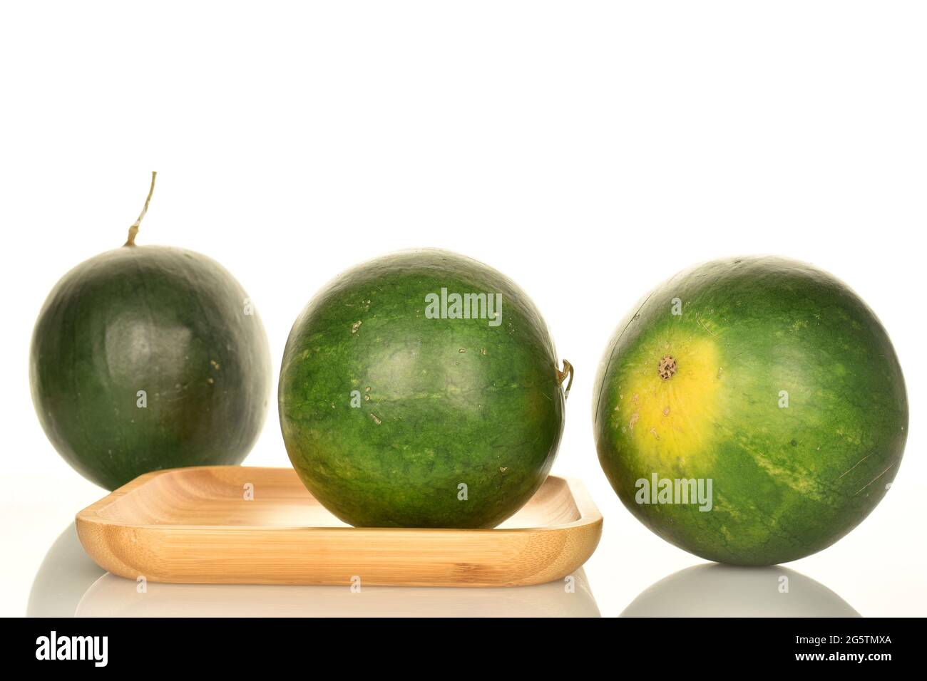 Three ripe organic watermelons with a bamboo plate, close-up, on a ...