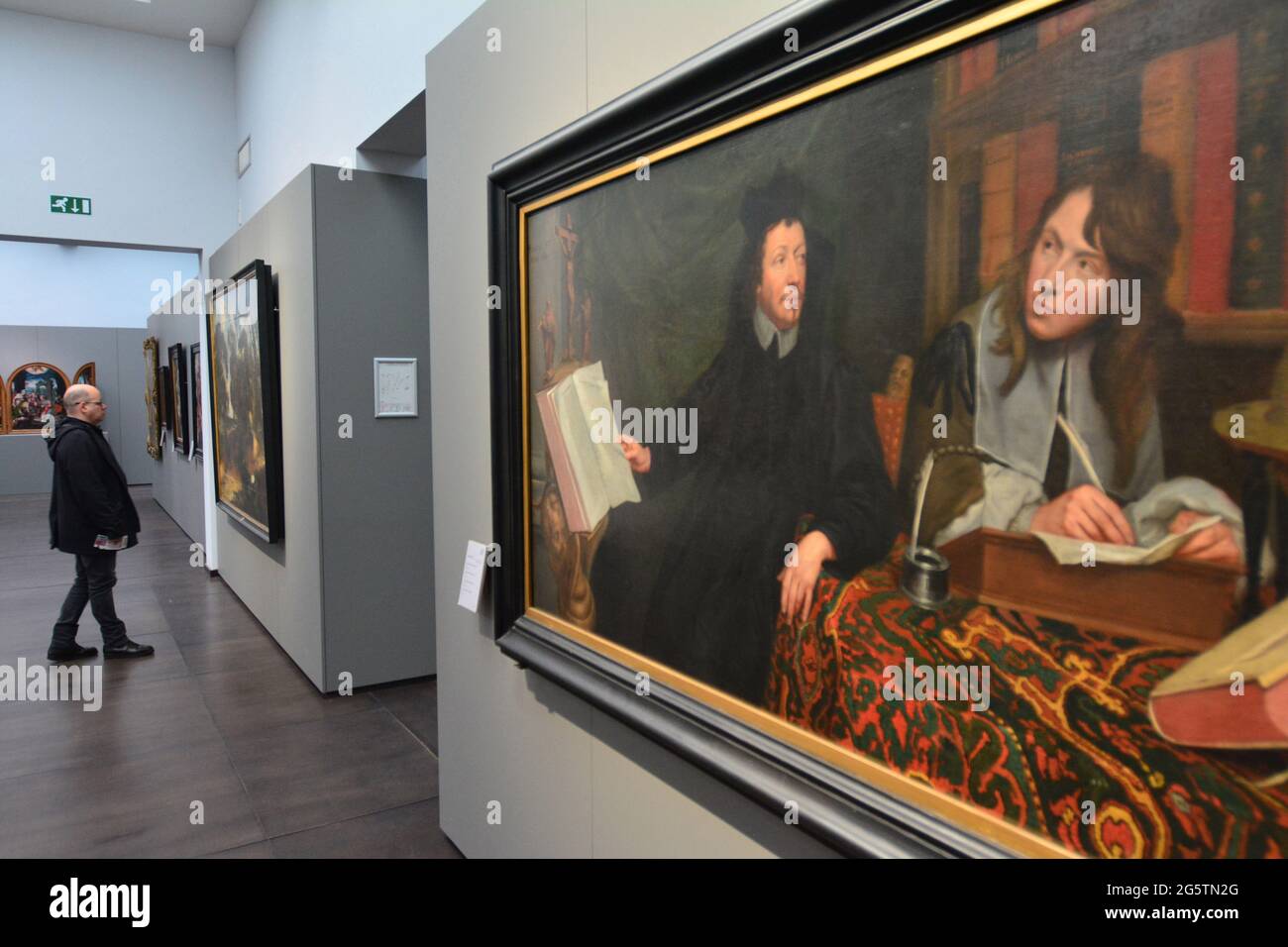 BELGIUM. FLANDERS. BRUGES. MAN LOOKING AT SOME PAINTINGS FROM THE ...
