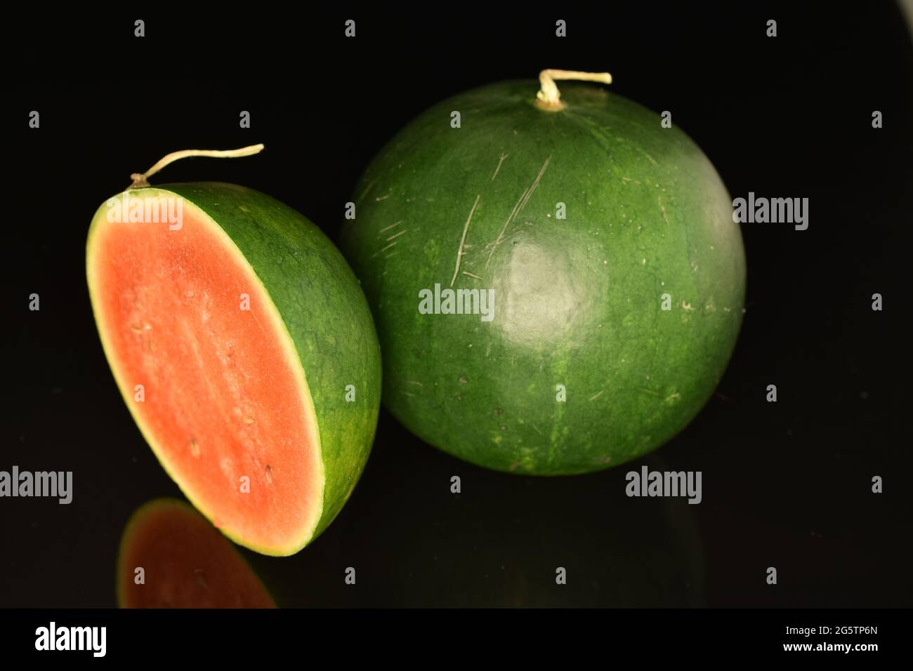One whole and one half of a juicy watermelon, close-up, on a black ...