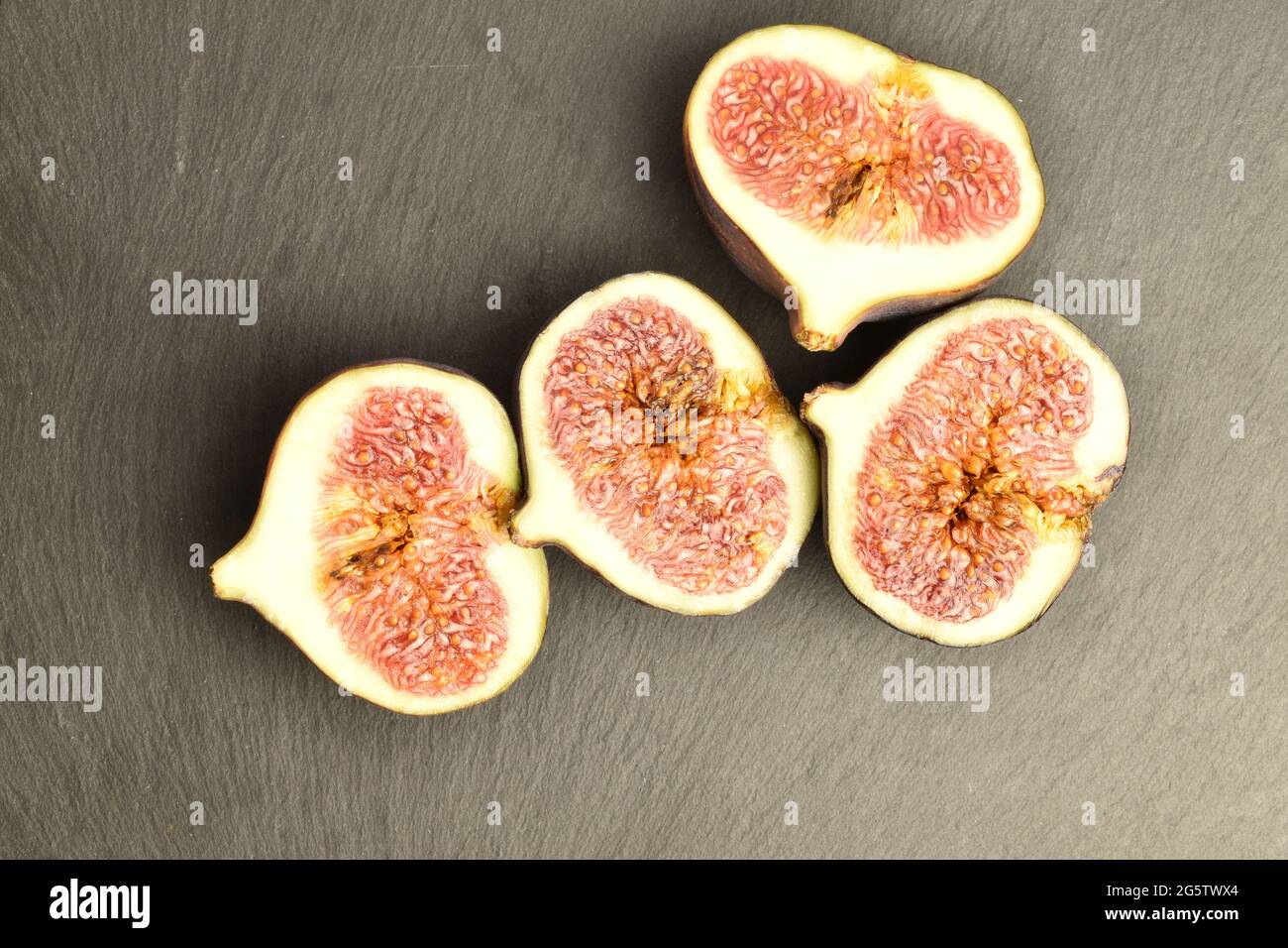 Four halves of ripe organic figs, close-up, on a slate board, top view ...