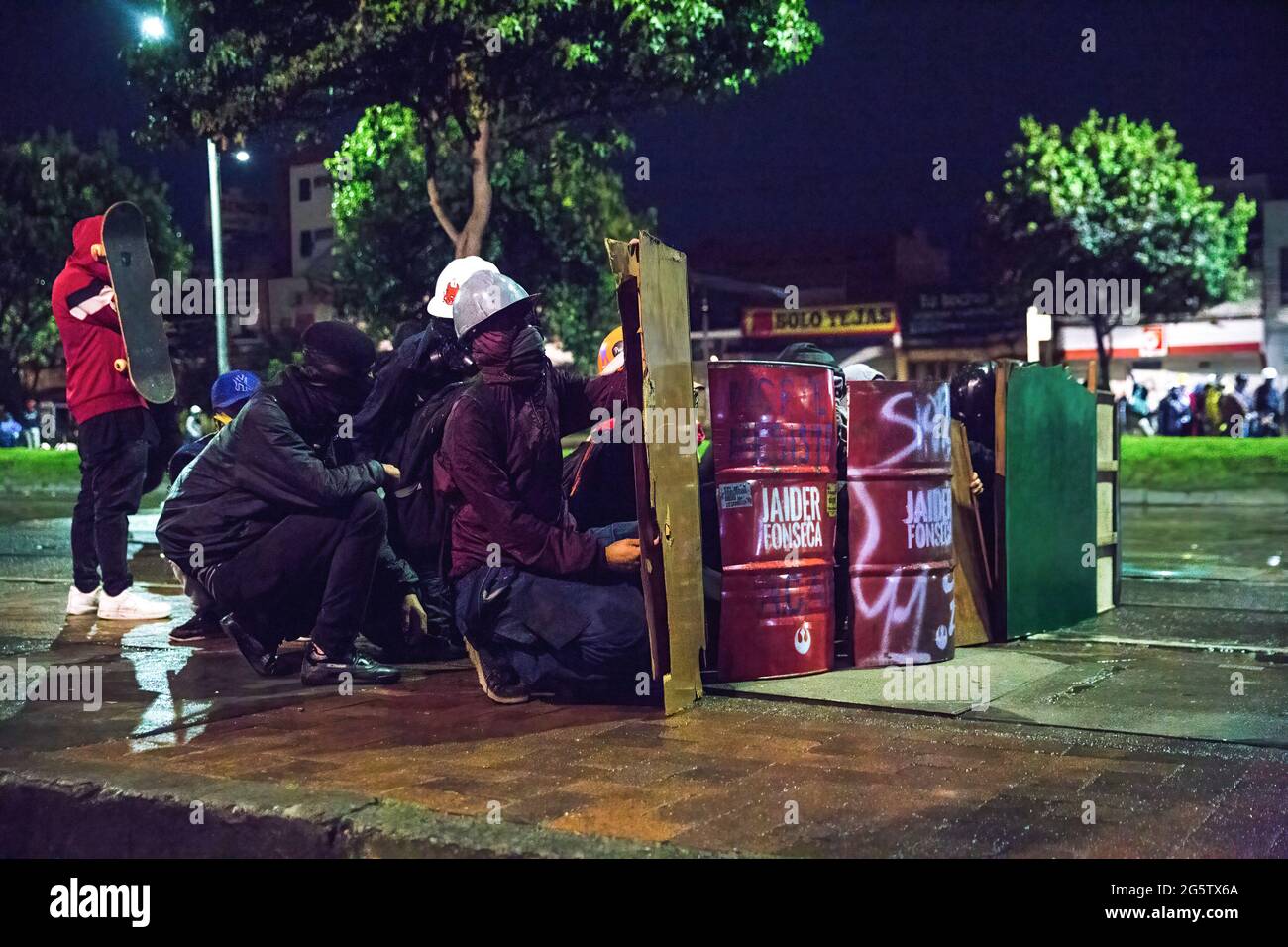 Bogota, Colombia. 27th June, 2021. Members of the front line take cover ...